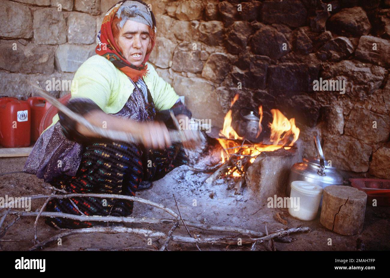 A Kurdish woman prepares a fire to make tea in the small village ...