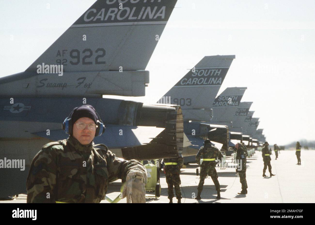 A line of F-16 Fighting Falcons with fire bottles and personnel ...