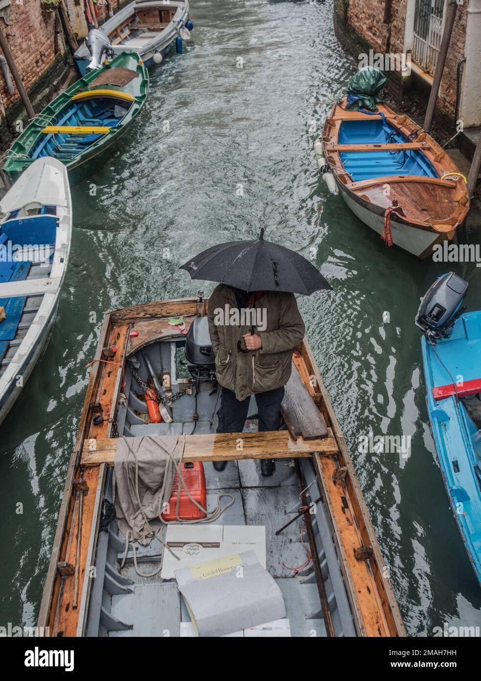 Canal with boats and one person with umbrella in the rain, Venice. Italy Stock Photo - Alamy