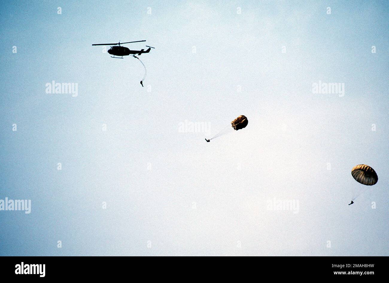 Airborne troops parachute from a U.s. Army UH-1 Iroquois helicopter ...