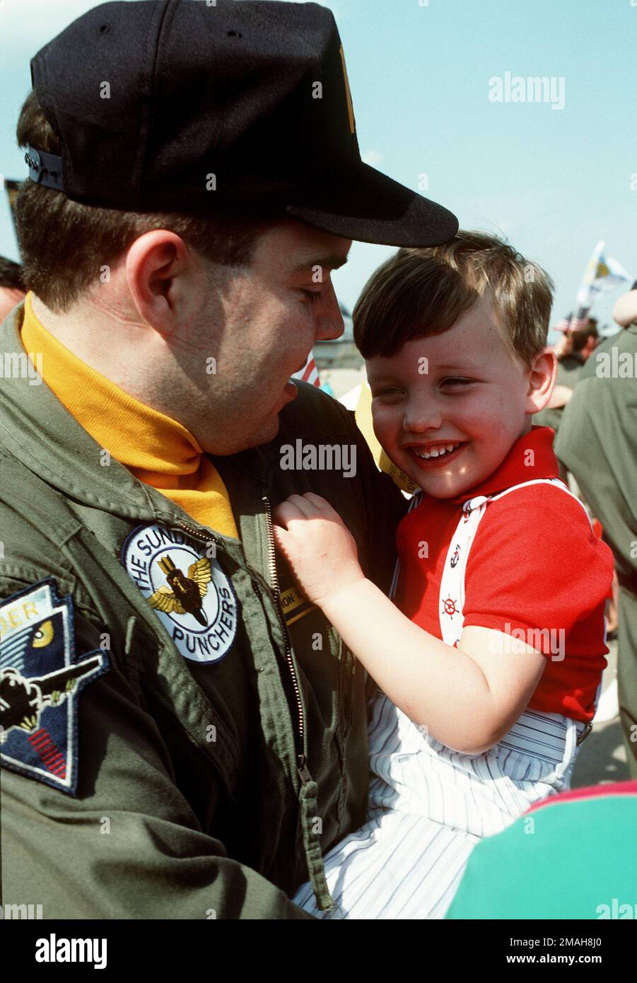 A member of Attack Squadron 75 (VA-75) holds his son. Elements of VA-75 ...