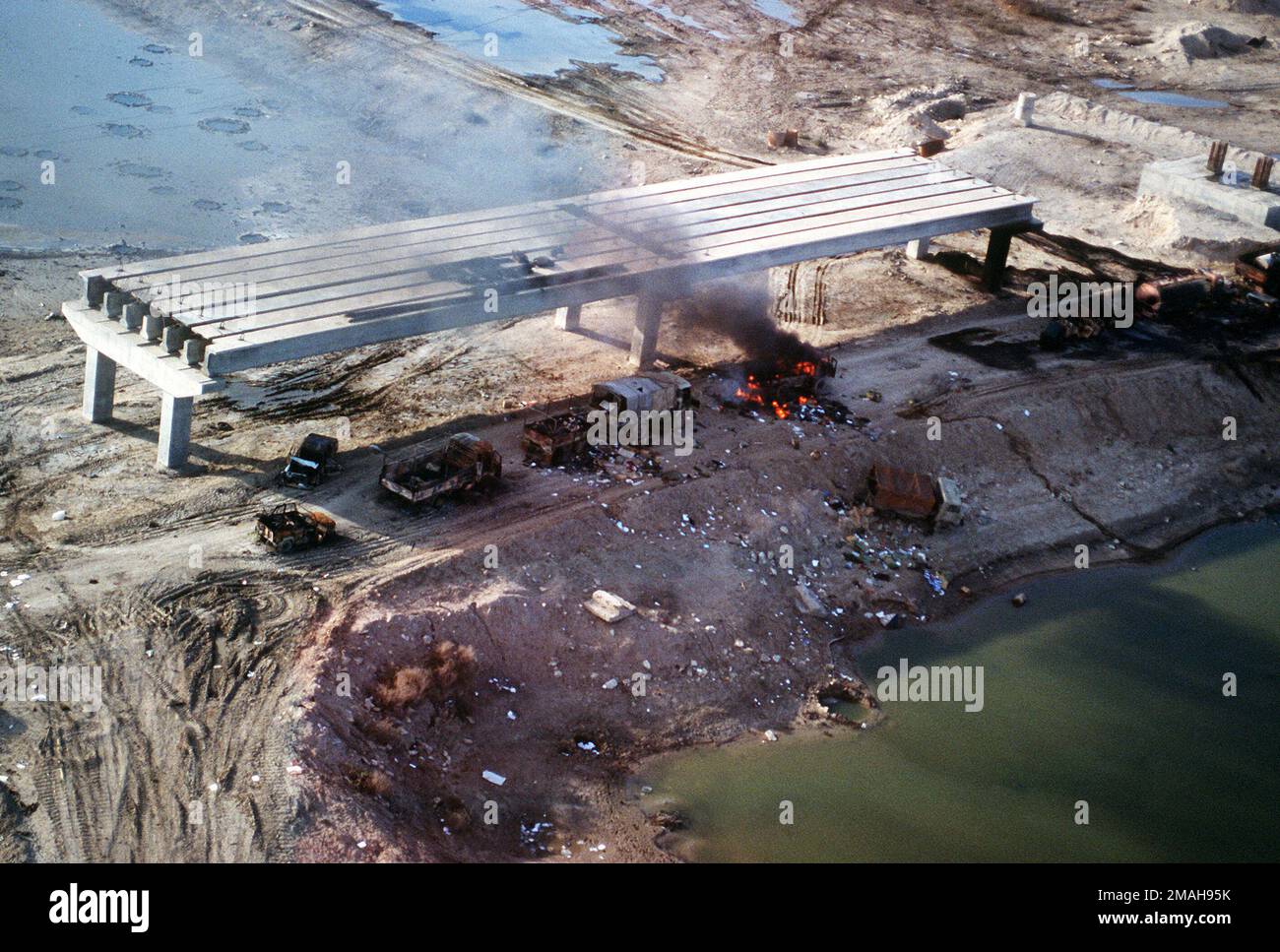 Demolished Iraqi vehicles line a roadway near a section of elevated ...
