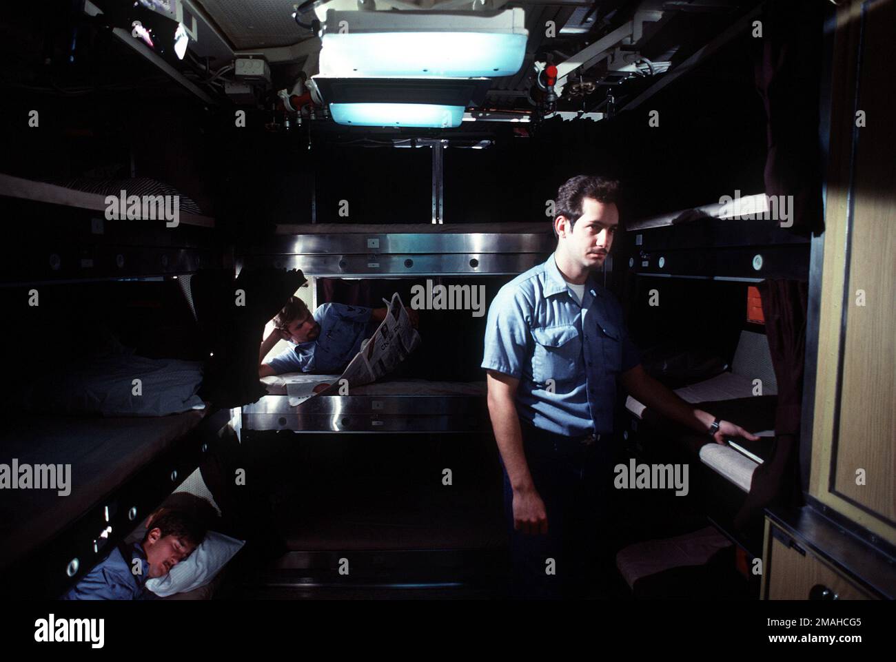 Three crewmen relax in the enlisted berthing compartment during ...