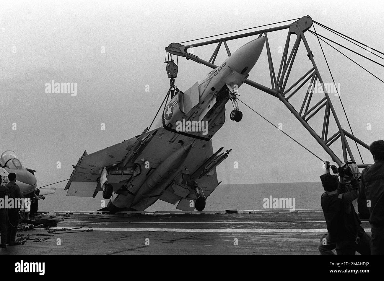 A crane is used to lift an F-4 Phantom II aircraft away from the port ...
