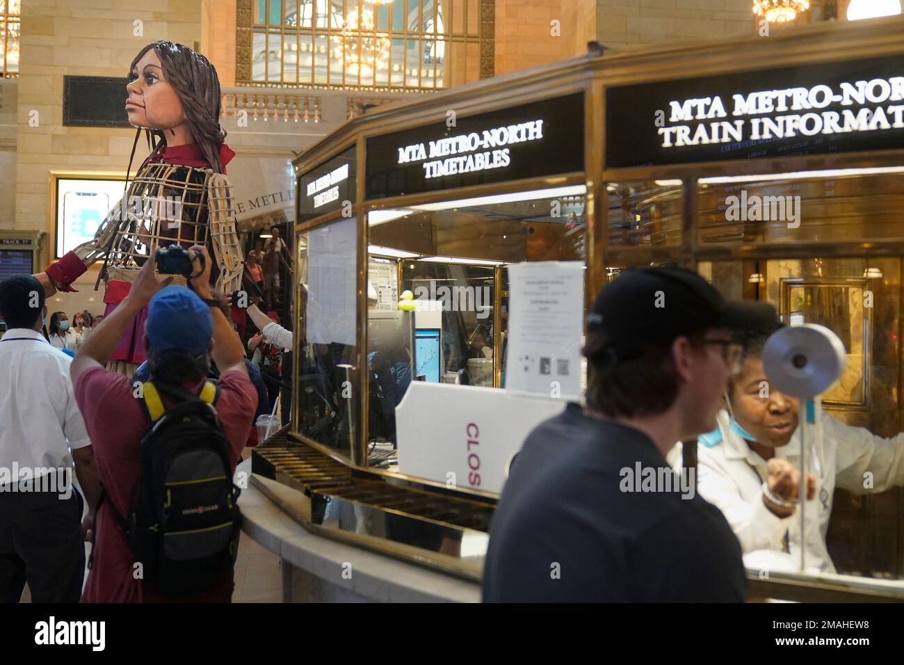 An MTA employee, right, helps a commuter as a large puppet named Little ...