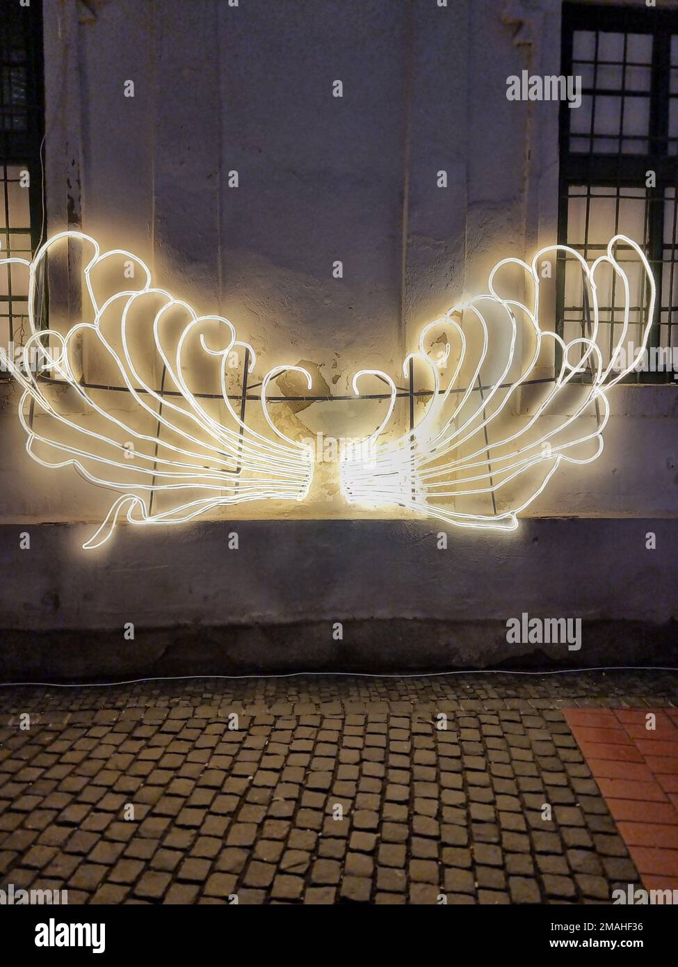 Yellow decorative lights on a wall in shape of facing each other swans ...