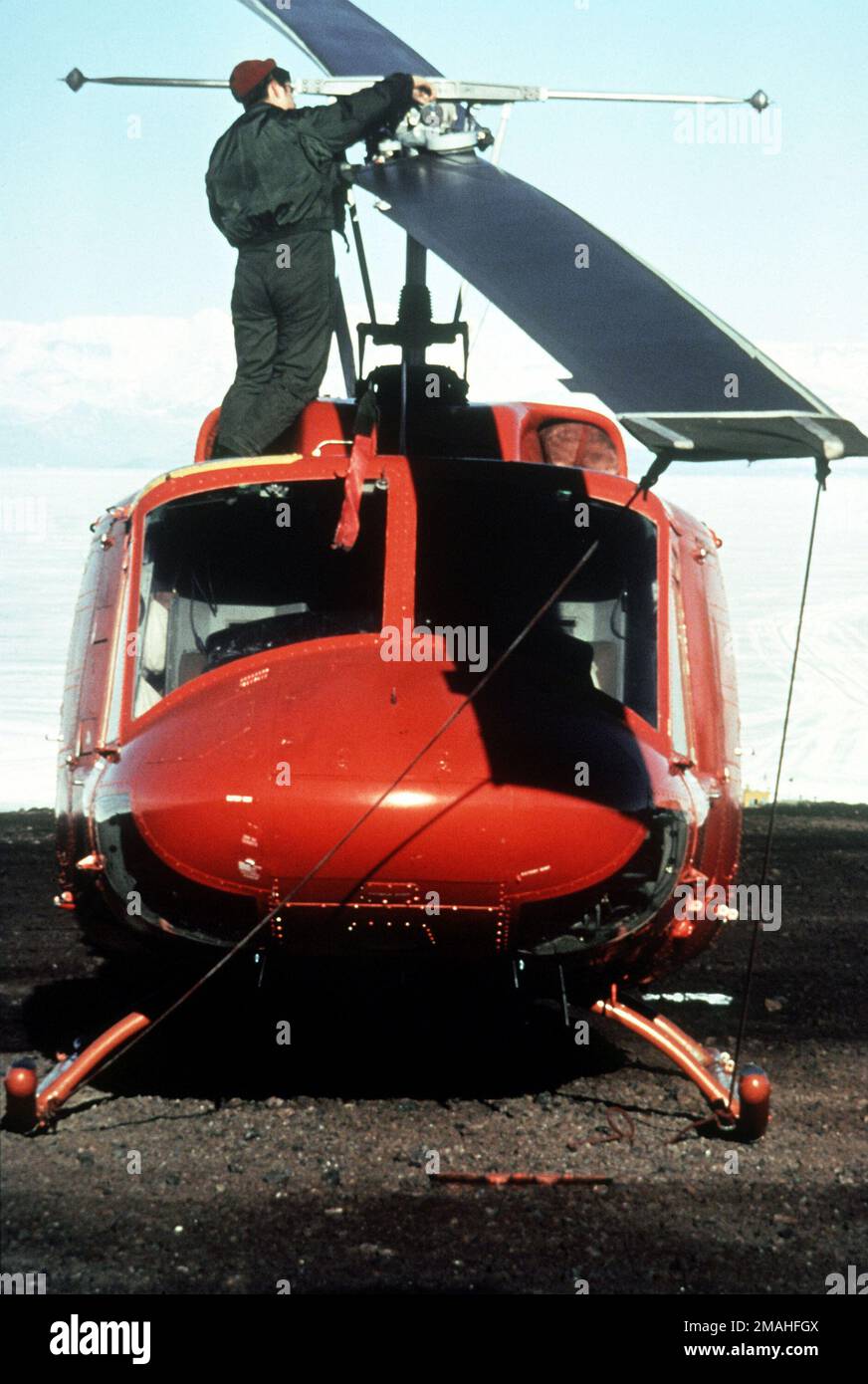 An Antarctic Development Squadron Six crewman preflights a UH-1N ...
