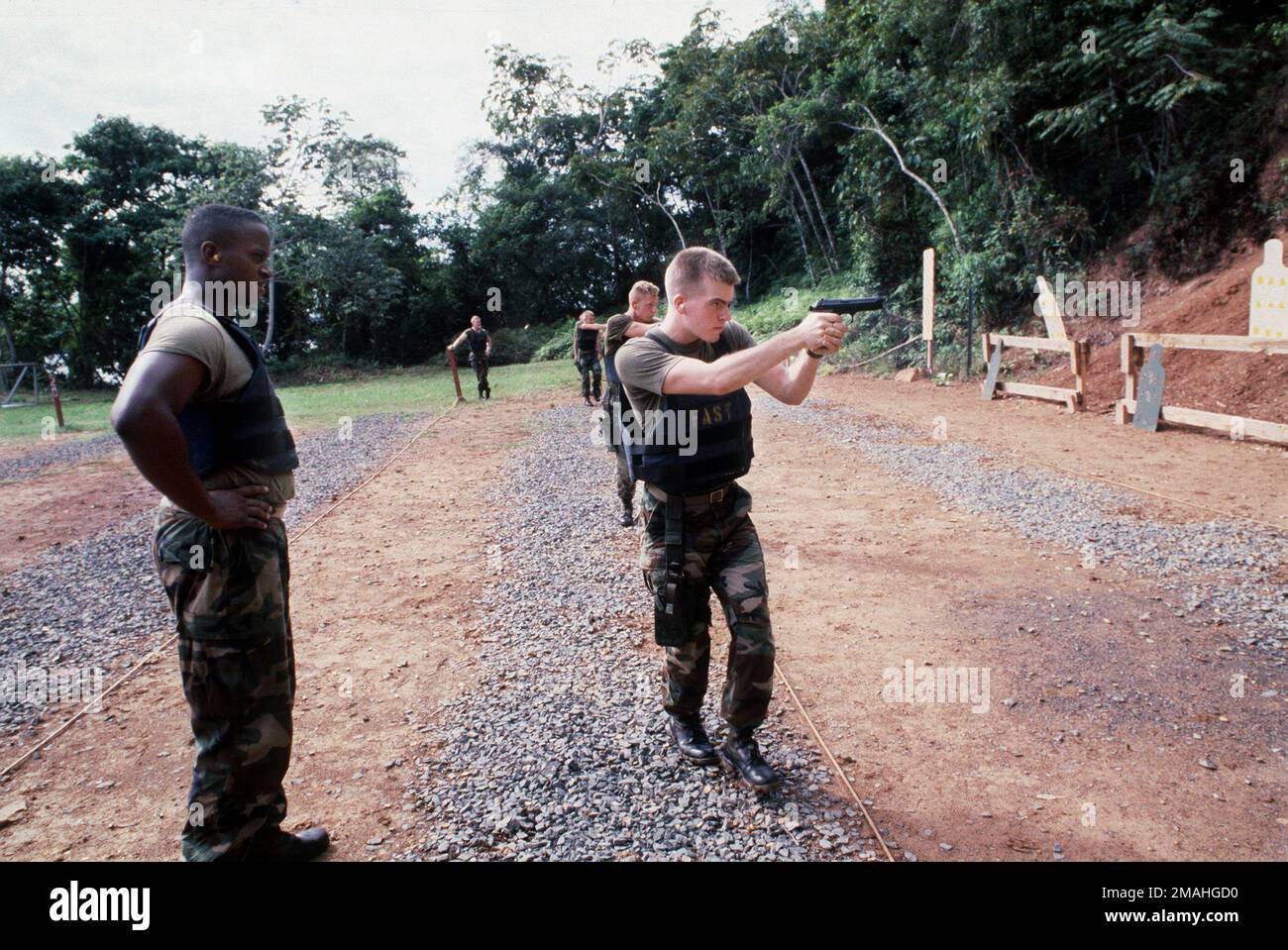 Marines fire their M9 9 mm pistols while moving down the firing line at ...