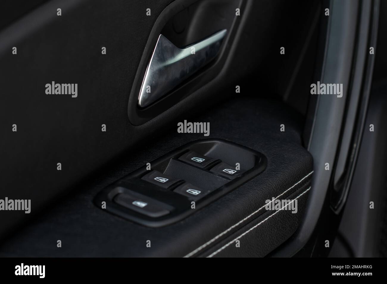Car door handle with power window control. Dark leather interior of ...