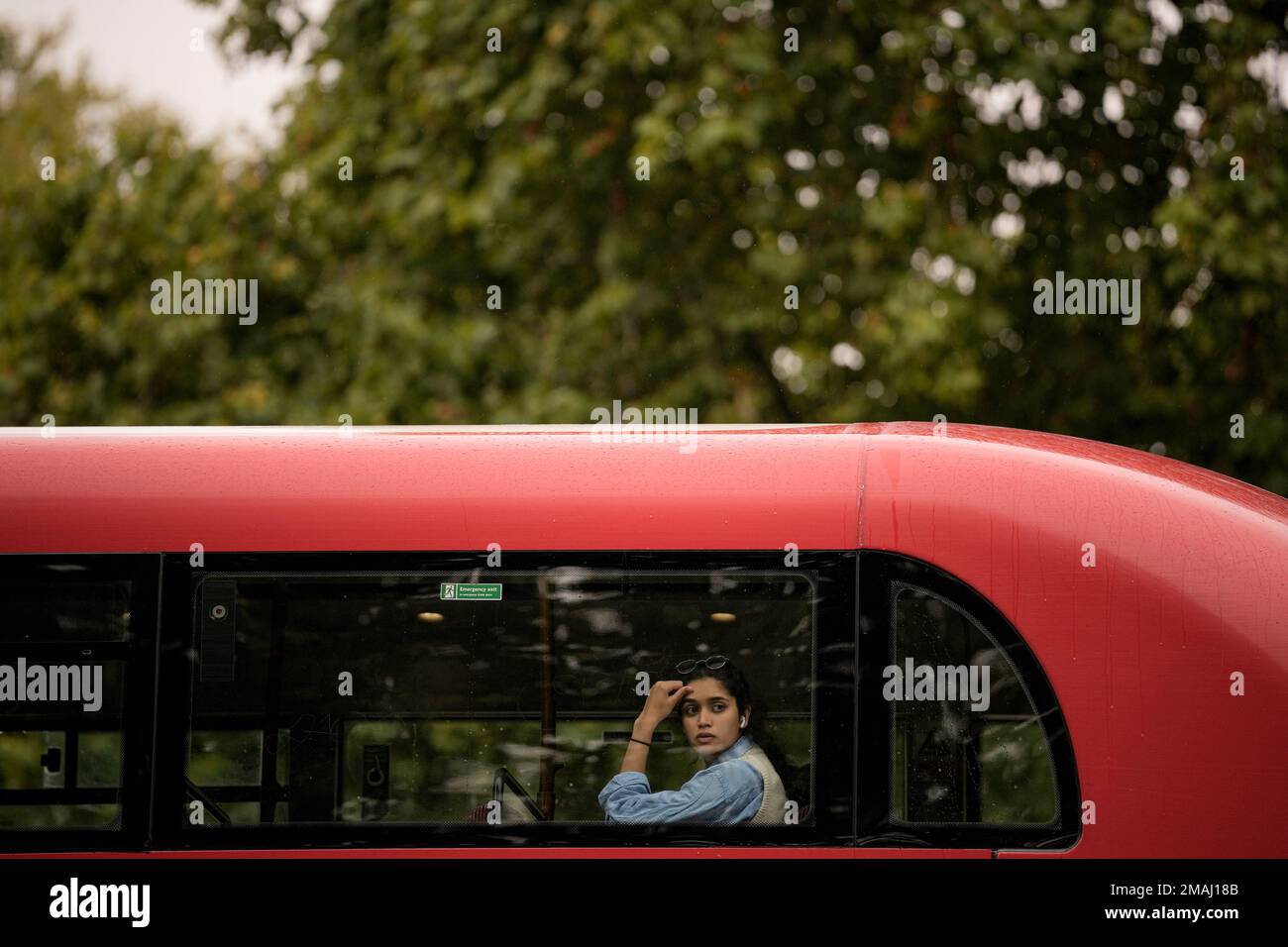 A woman looks from a bus at people lining up the street to see the ...
