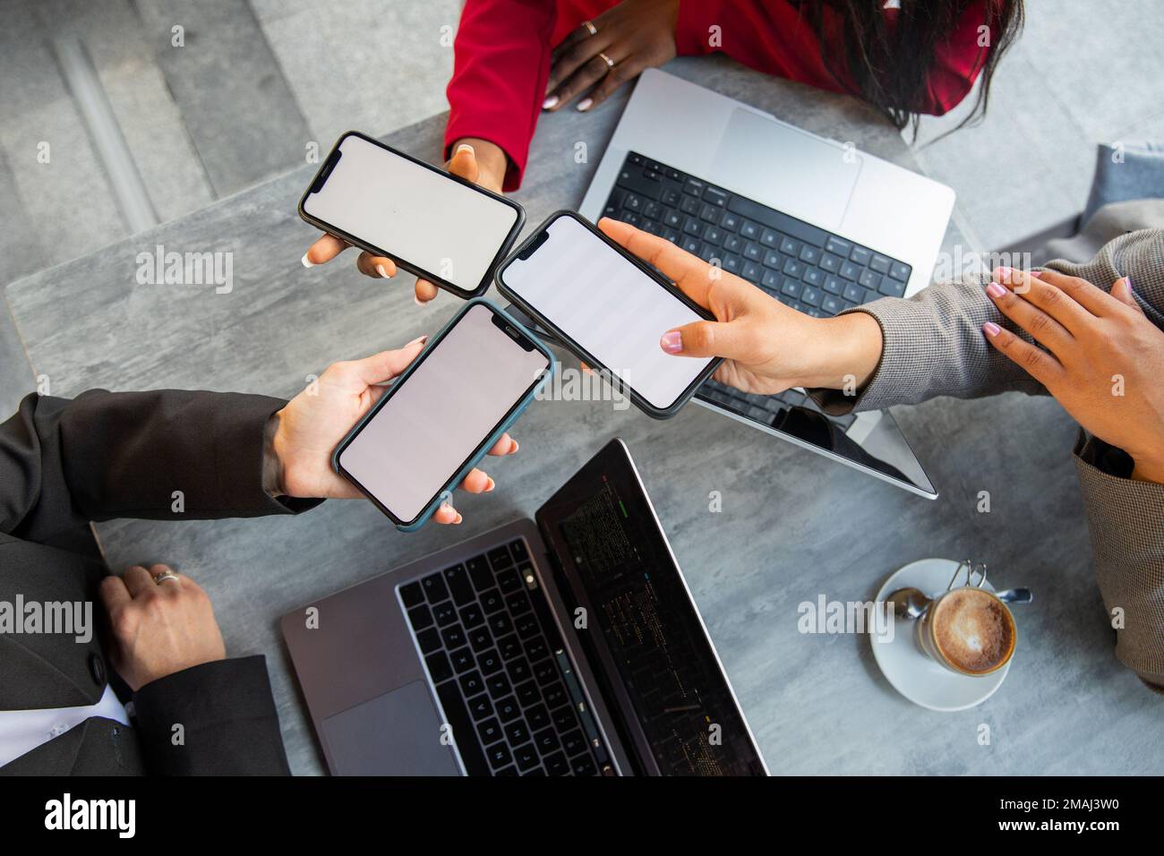 Three businesswomen join phones at center table, white screens with ...