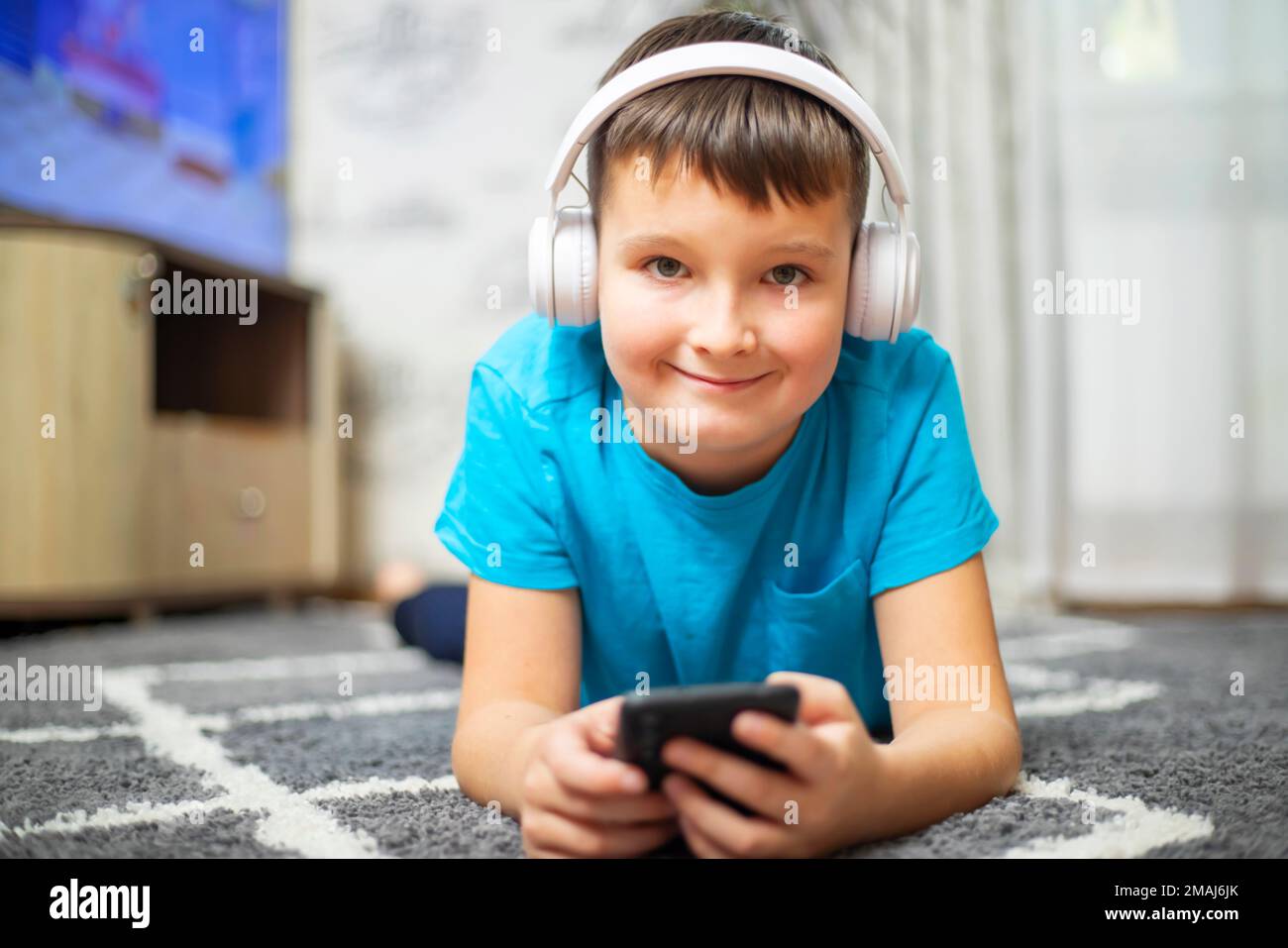 A child boy with phone and headphones is lying on the floor Stock Photo ...