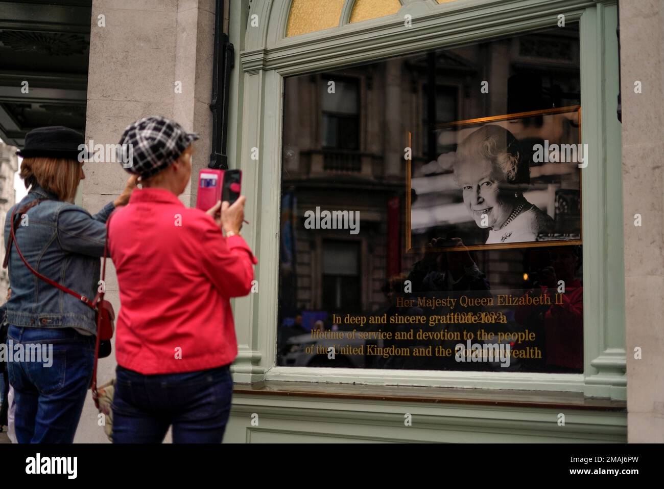 People take pictures to a shop windows that displays a portrait of the ...