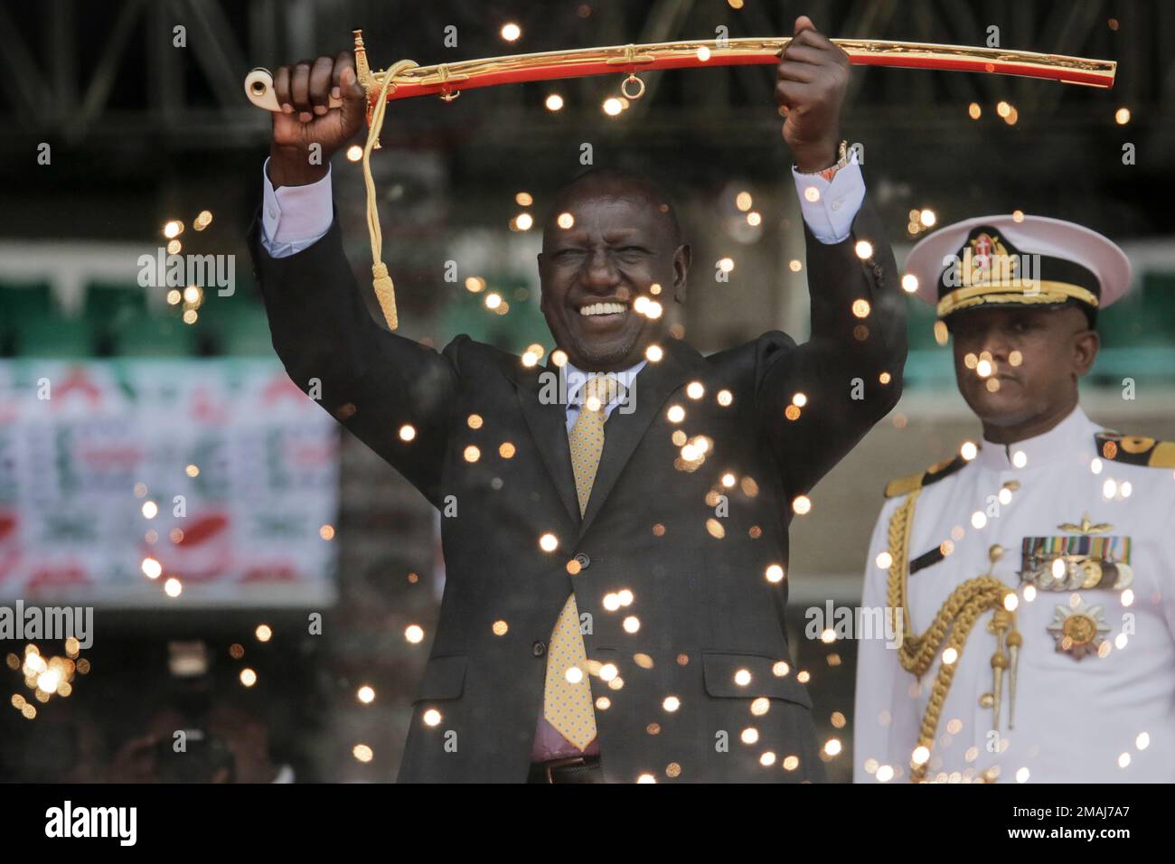 Kenya's new president William Ruto, seen behind fountain fireworks, holds up a ceremonial sword ...