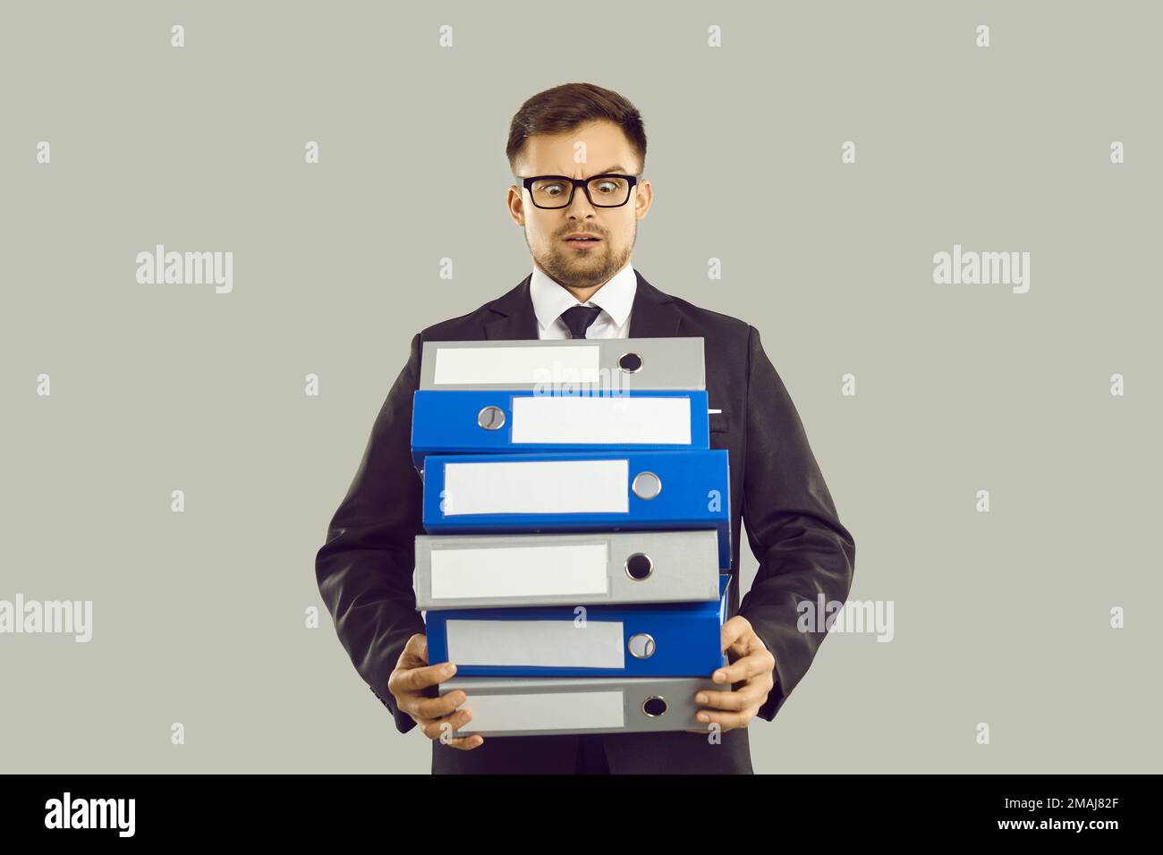 Angry office worker with pile of papers and documents is stressed by ...