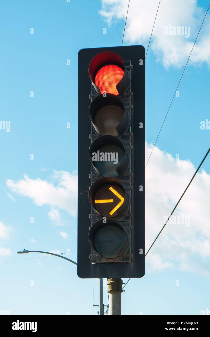 Red color and yellow arrow on the traffic light with cloudy sky on the ...
