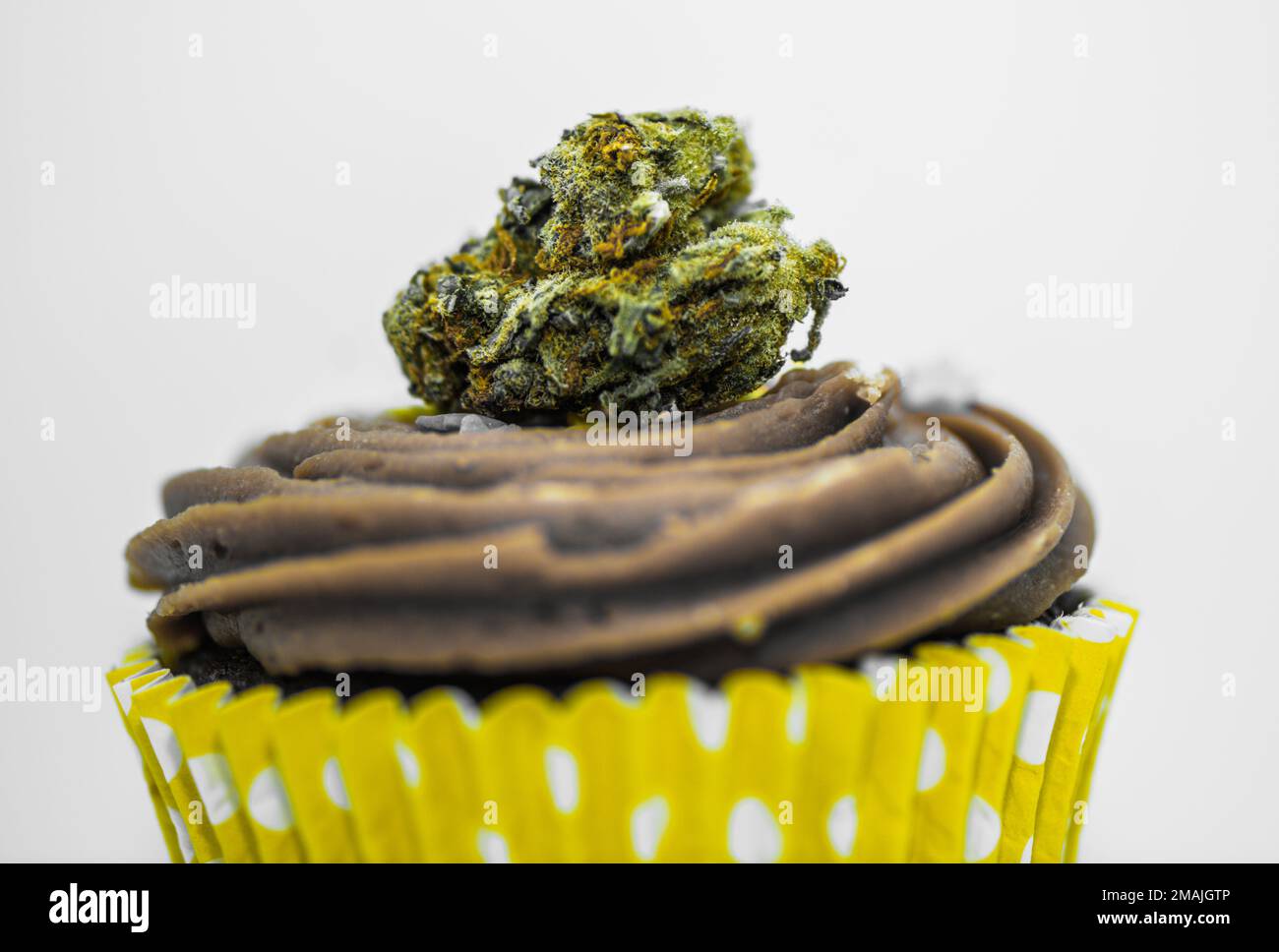 A close-up shot of a Cannabis Bud on a cupcake isolated on a white ...
