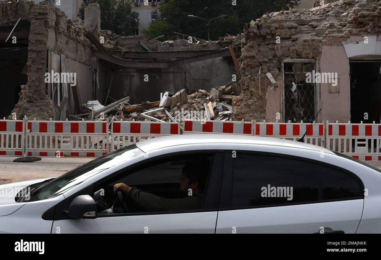 People in a car pass by heavily damaged buildings after latest Russian ...