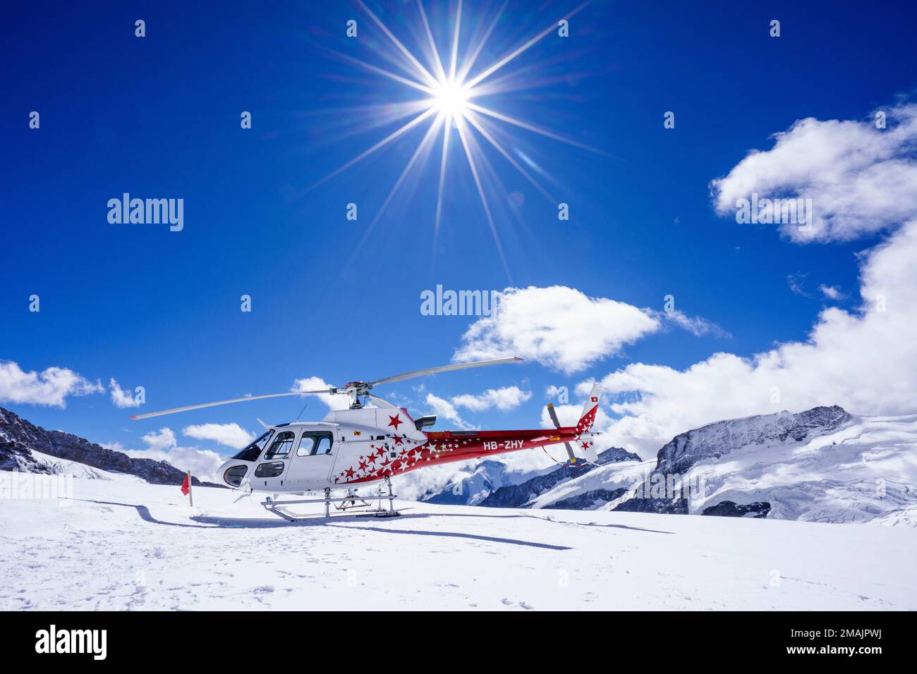 Swiss helicopter with red and white stars stands on Aletsch Glacier low ...