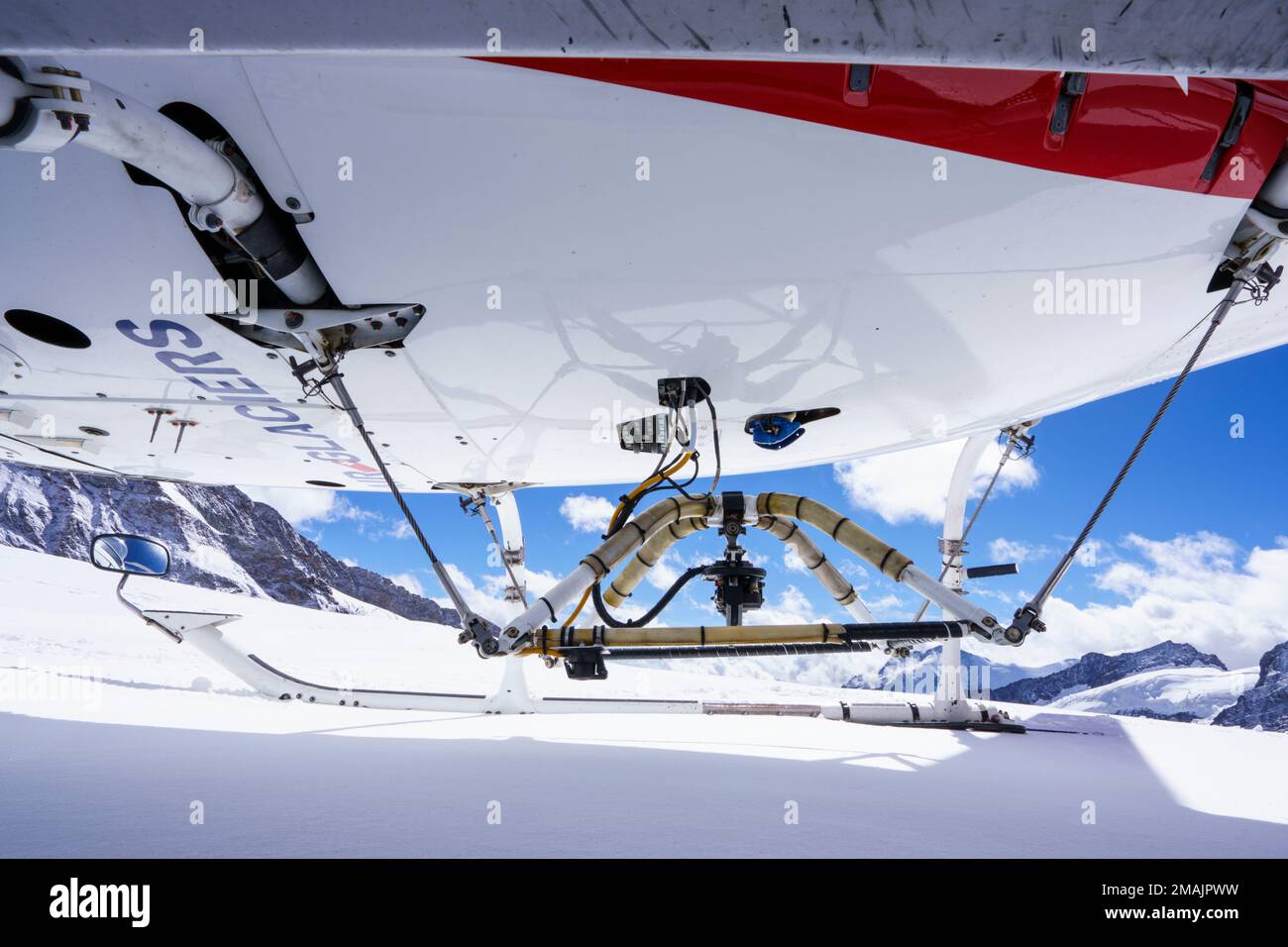 Helicopter underneath stands on snow, background blue sky with clouds ...