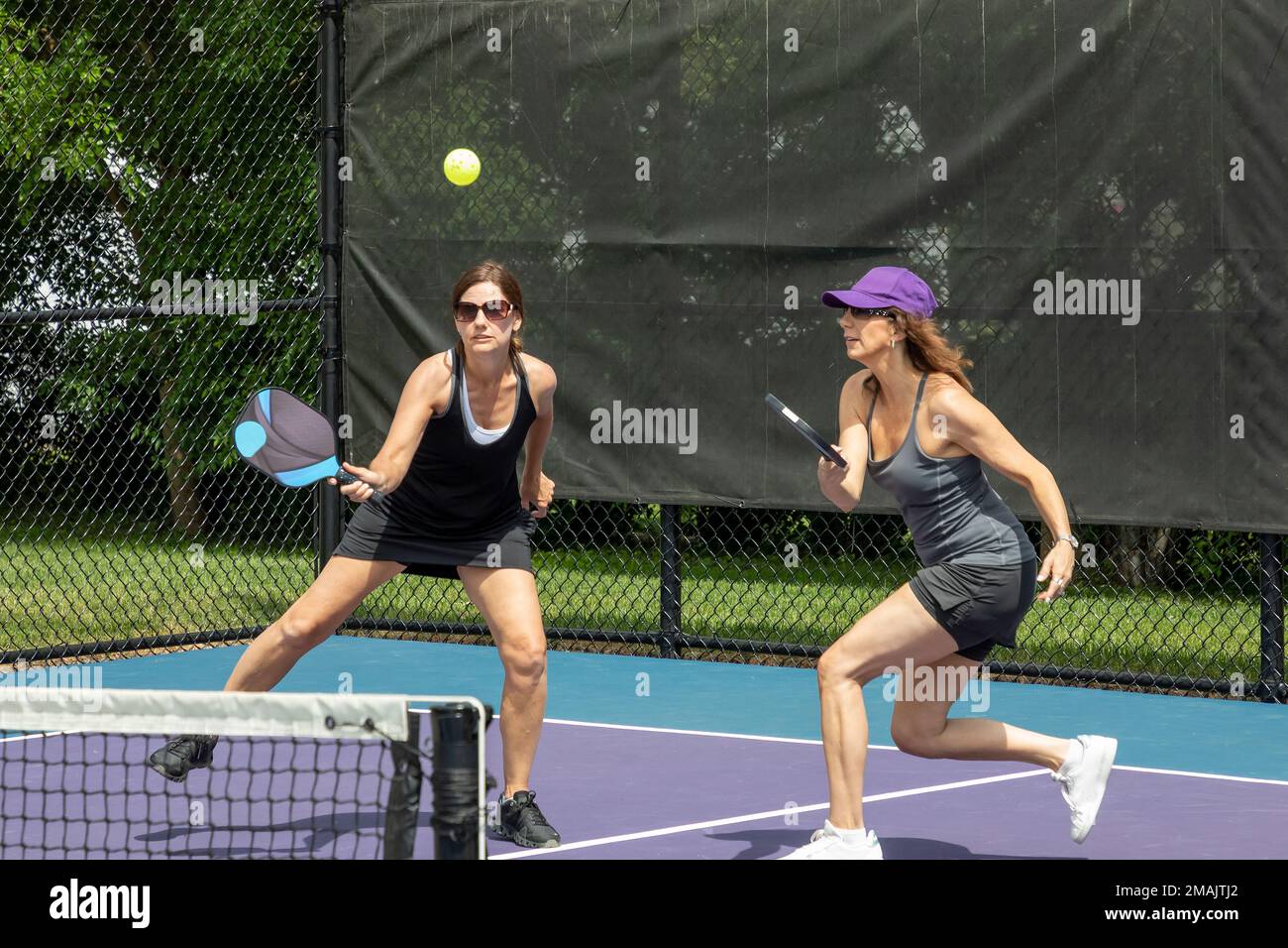 Two pickleball players prepare to return a ball on a suburban ...