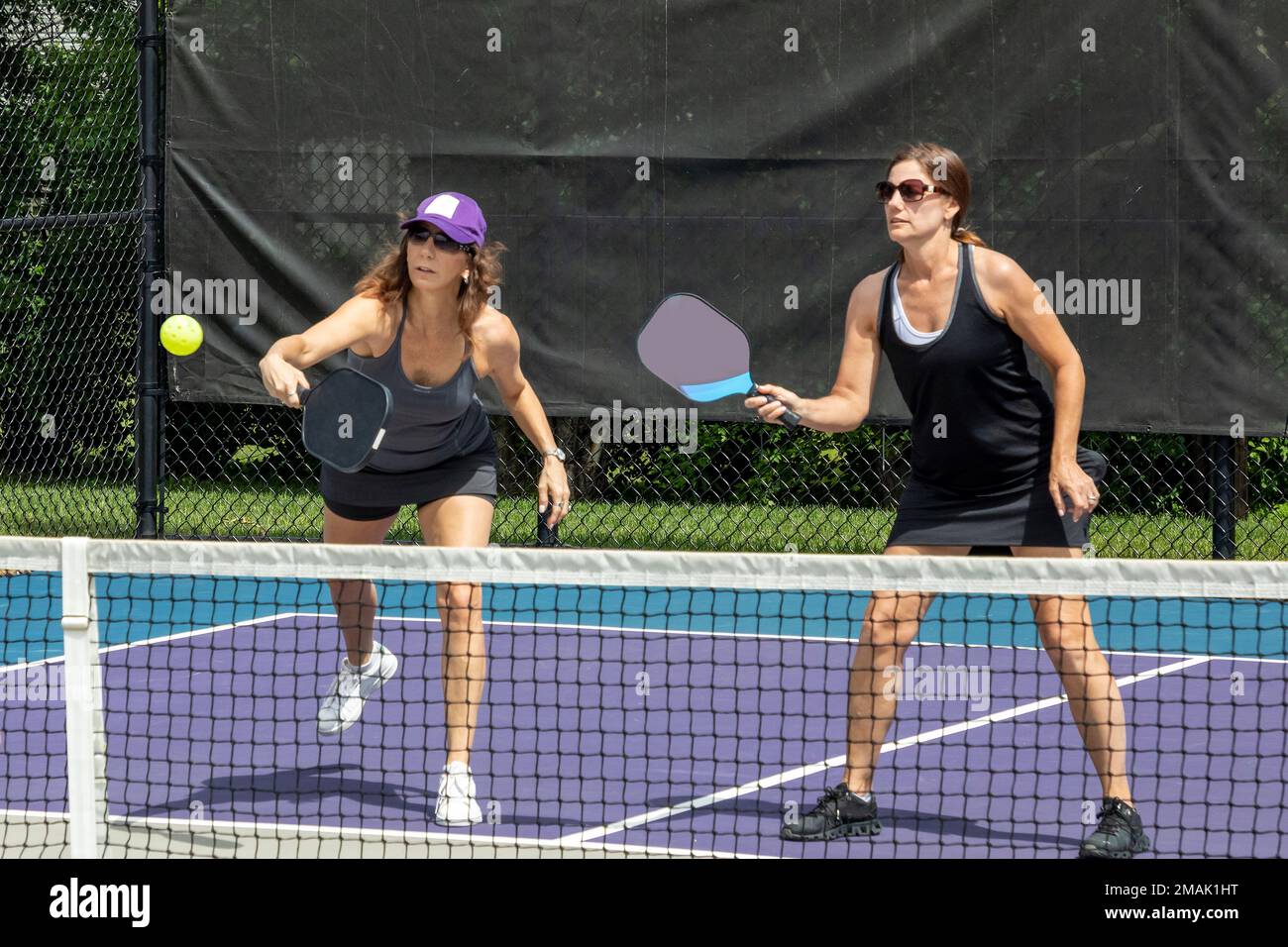Two pickleball players in action at the net on a suburban pickleball ...