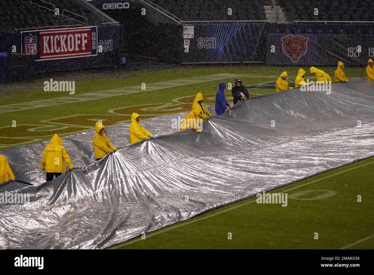 Workers remove a tarp from the turf at Soldier Field before an NFL ...