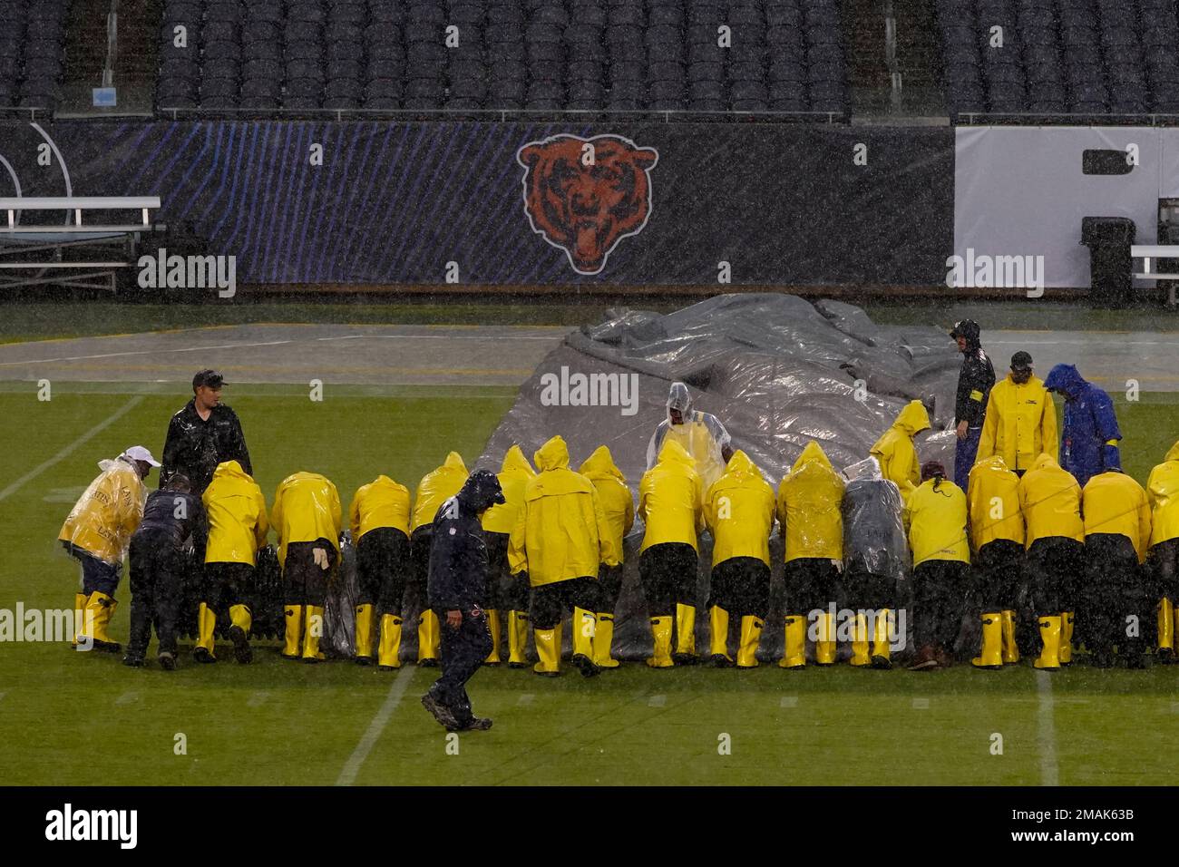 Workers remove a tarp from the turf at Soldier Field before an NFL ...