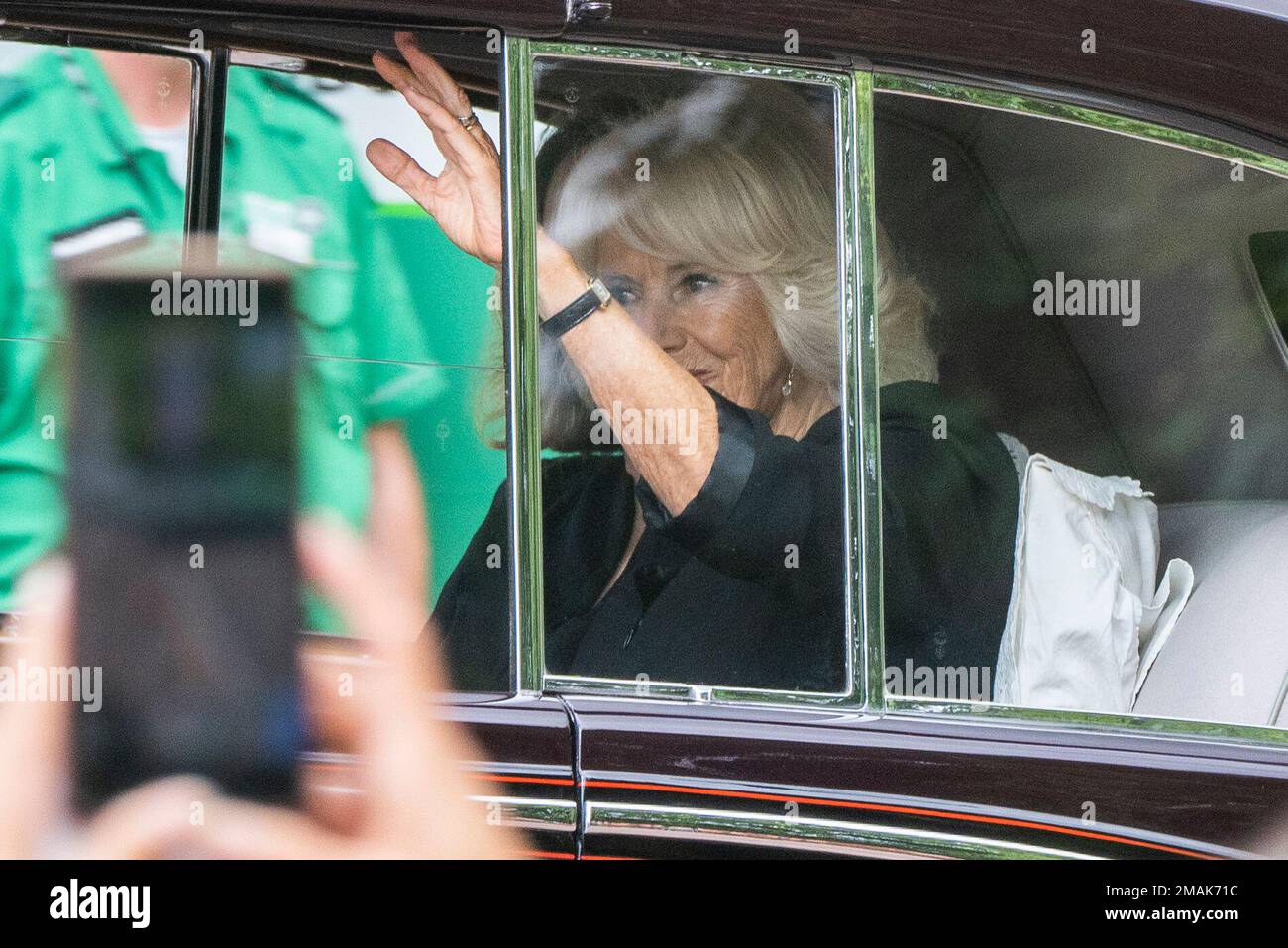 Camilla, the Queen Consort, waves to people in her car, in front of ...