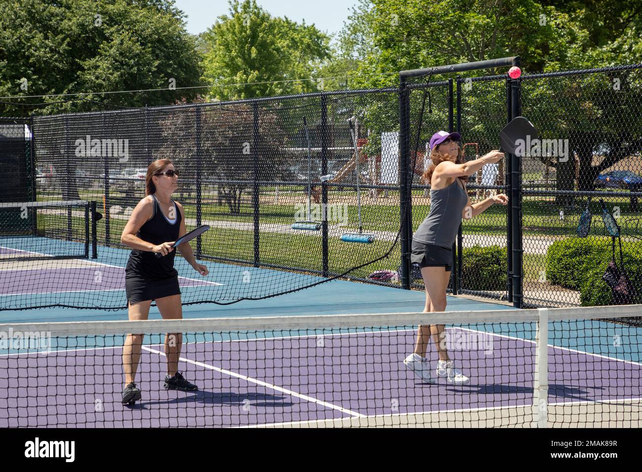 Two pickleball players in action on a suburban pickleball court during ...