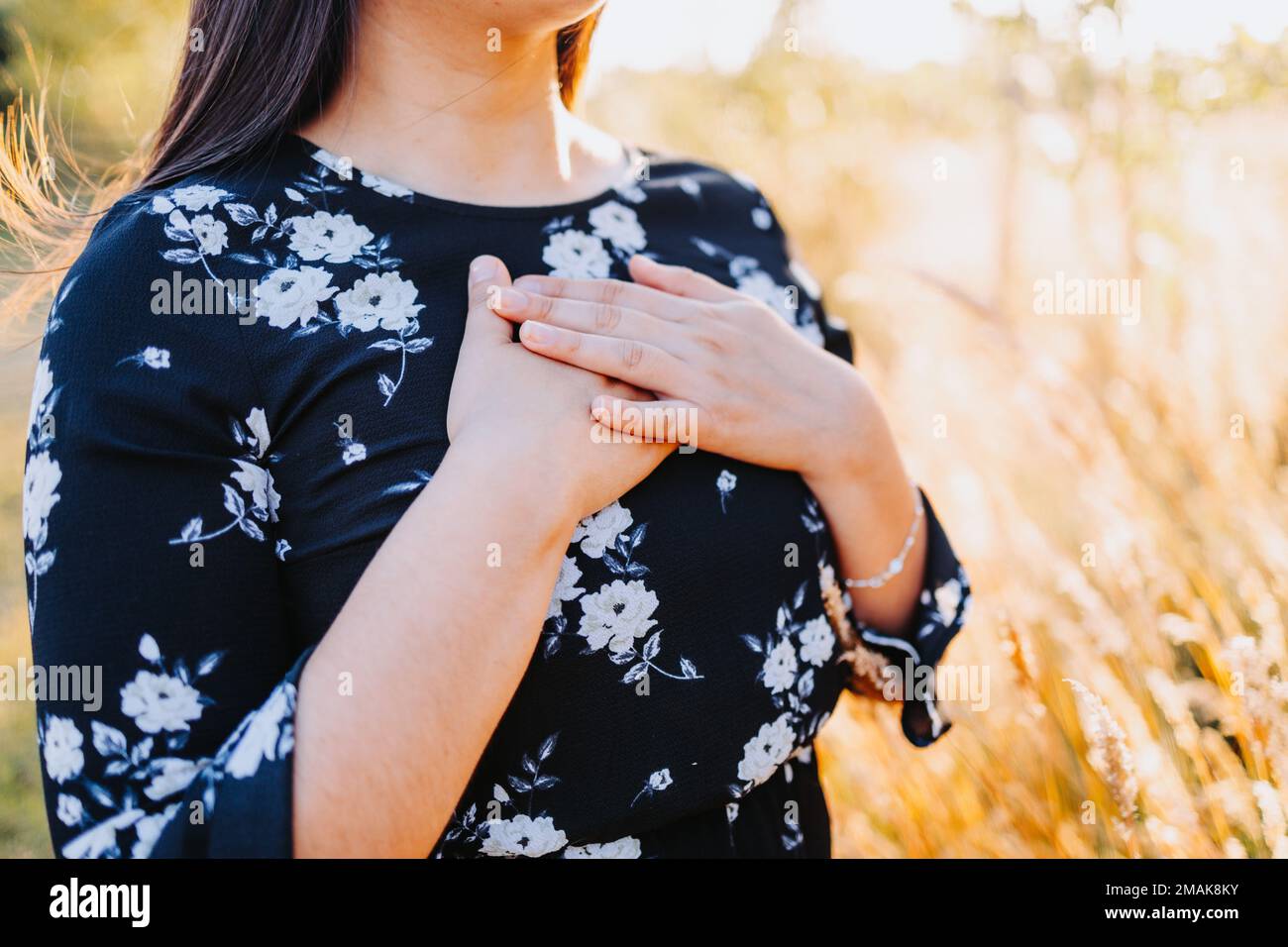 Hopeful woman putting hands on her heart in gratitude for God's ...
