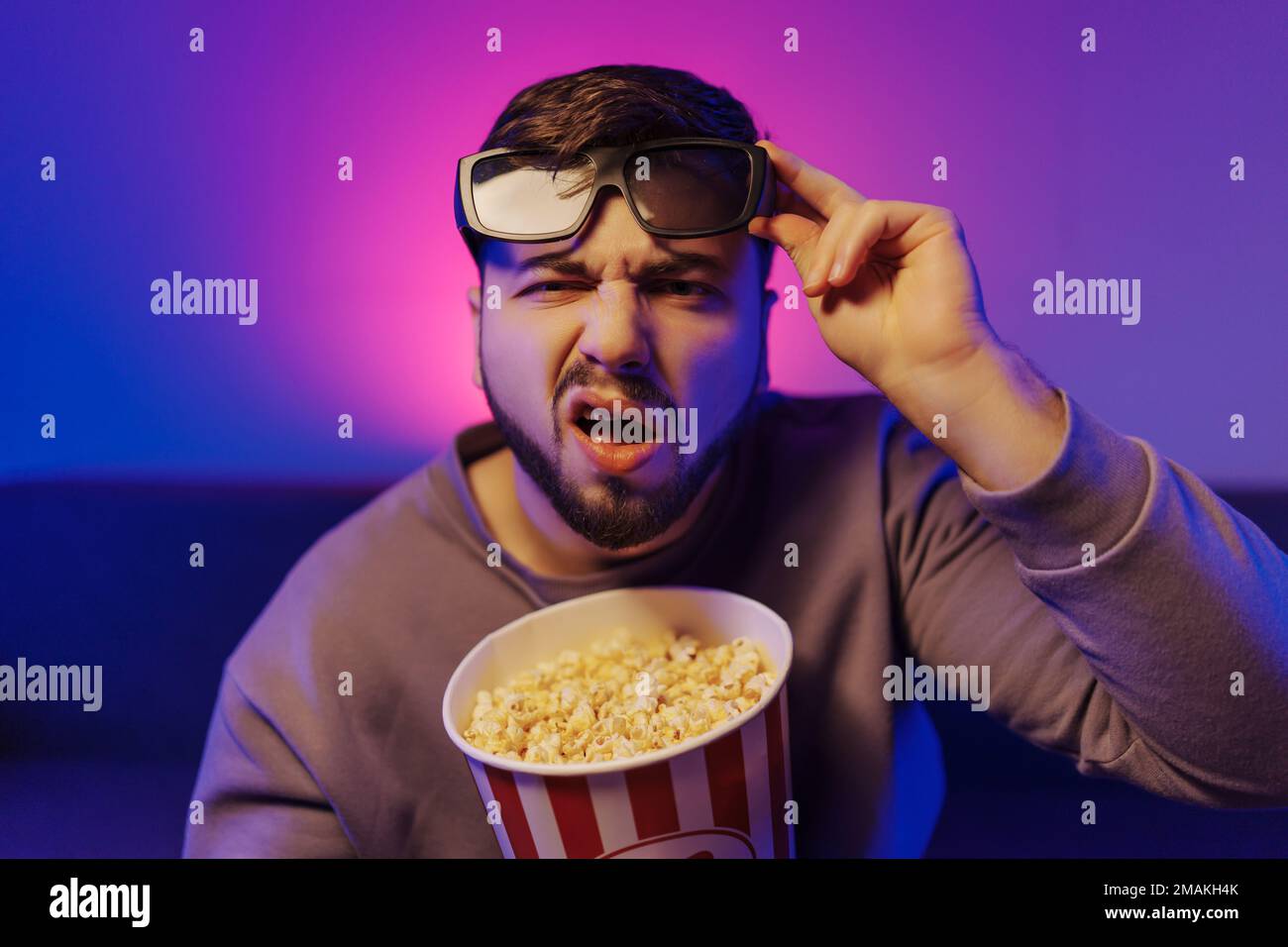 Dissatisfied man watching movie. The emotion of anger. Watching a movie with popcorn in 3D ...