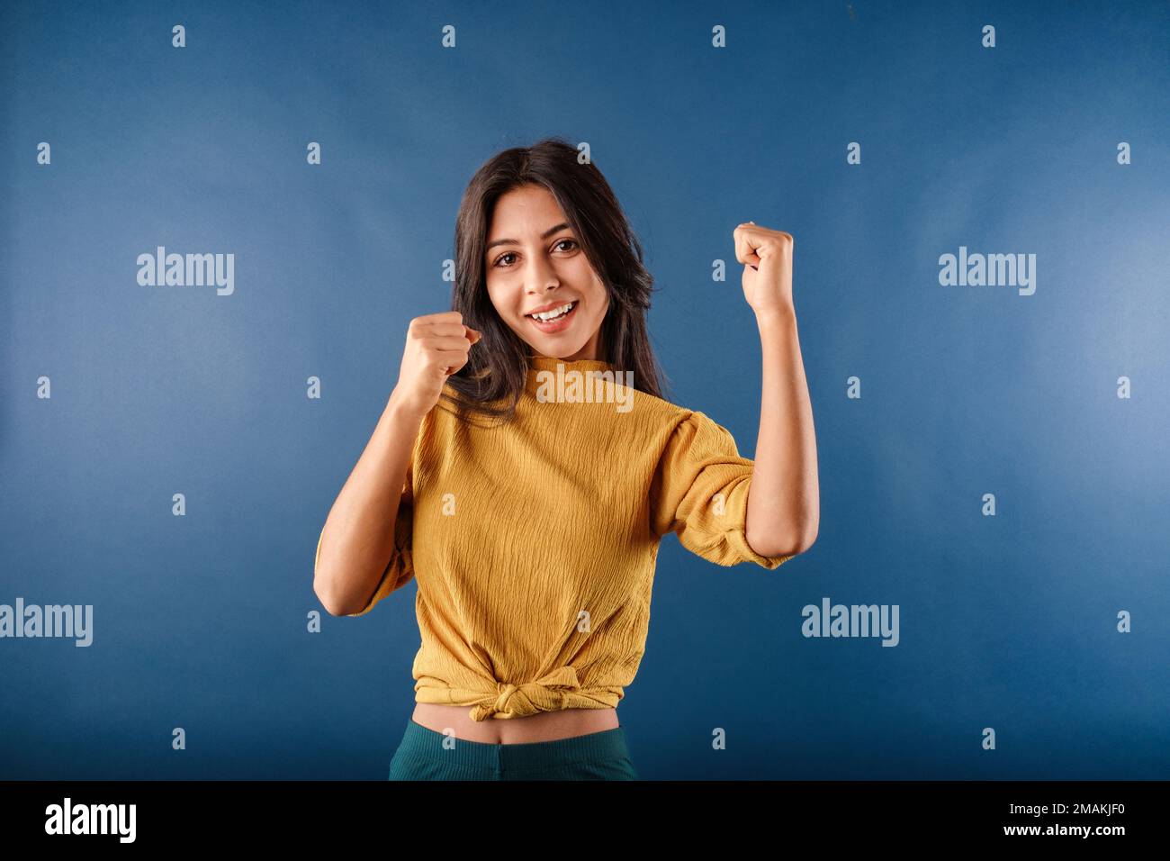 Cute dark-haired woman wearing casual top isolated over blue background ...