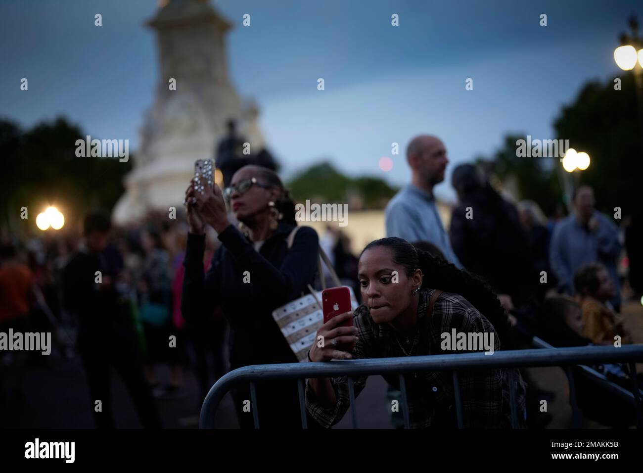 Mourners take images with their mobile phones as they gather to ...