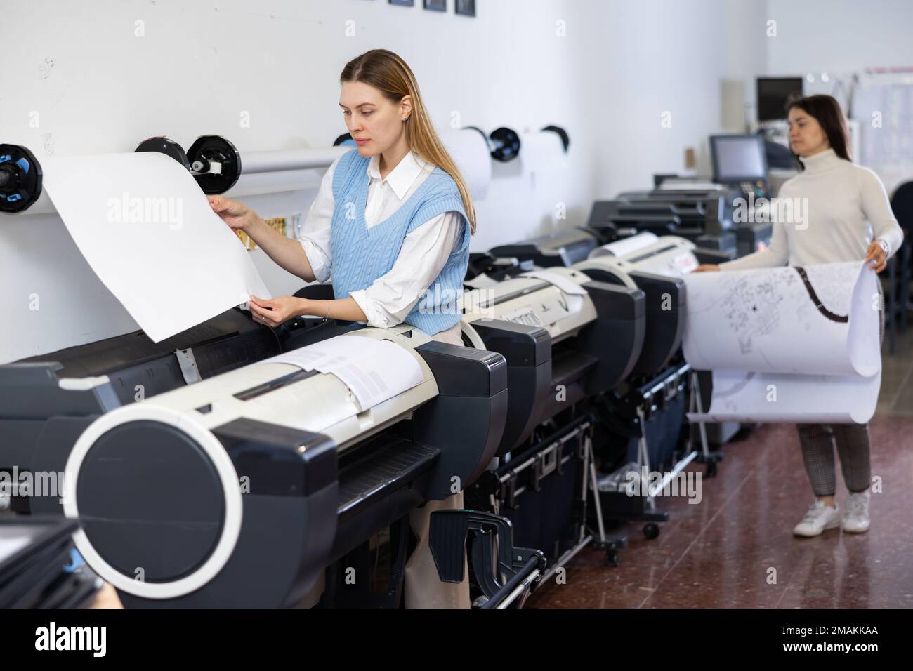 Woman using printer while working in print shop Stock Photo - Alamy