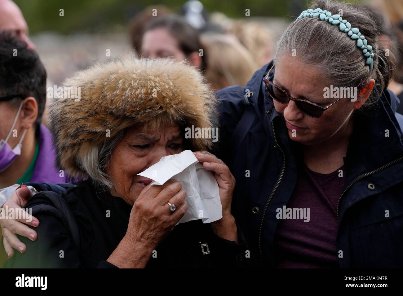 A weeping mourner is comforted by others who pay respect to the Queen ...