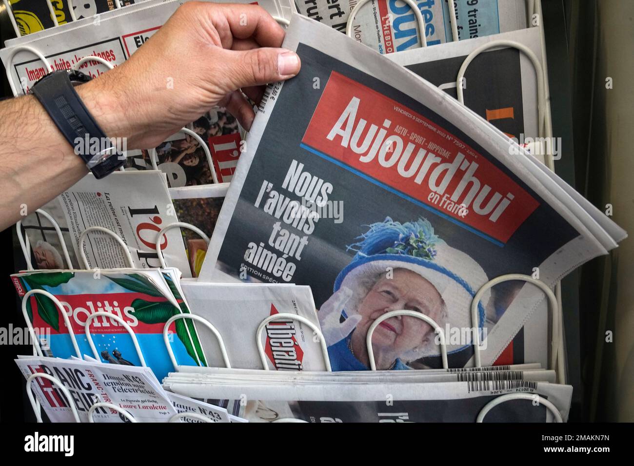 A man takes a newspaper fronting picture of Queen Elizabeth II in a ...