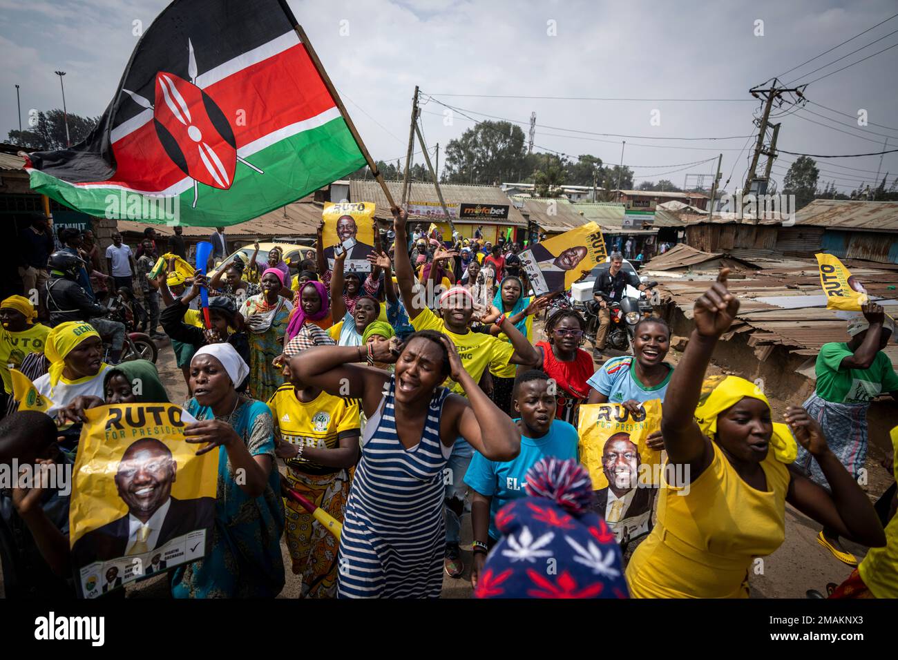 Supporters of William Ruto hold campaign posters of him and wave a ...