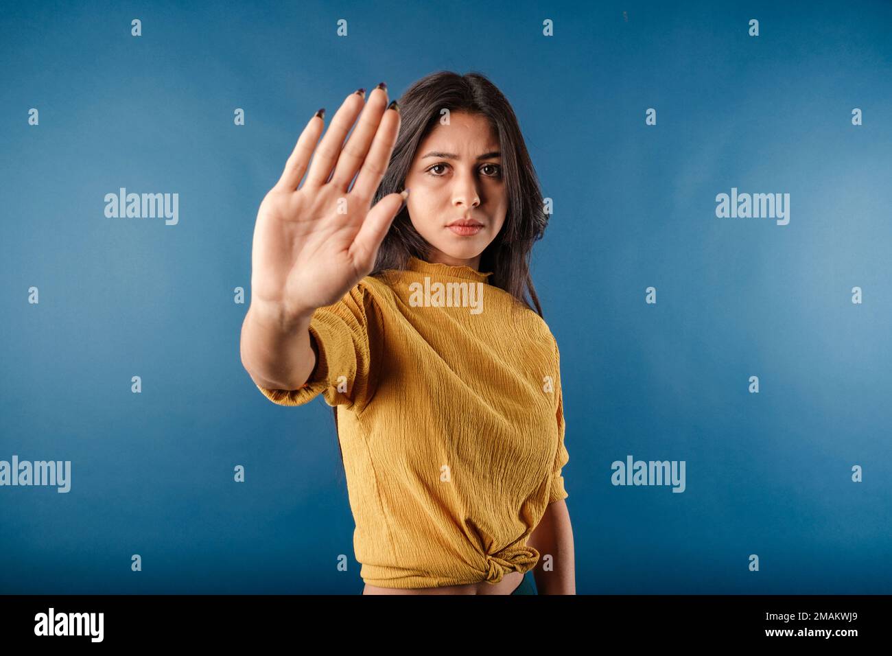 Portrait of brunette woman wearing mustard yellow t-shirt isolated over ...