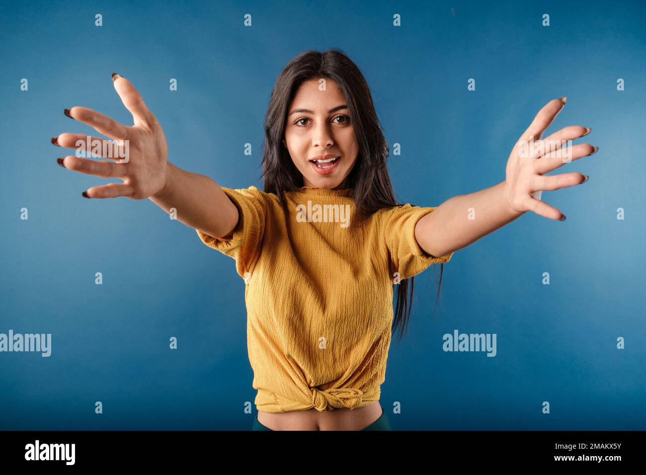 Young dark-haired girl smiling happy wearing yellow top isolated over ...