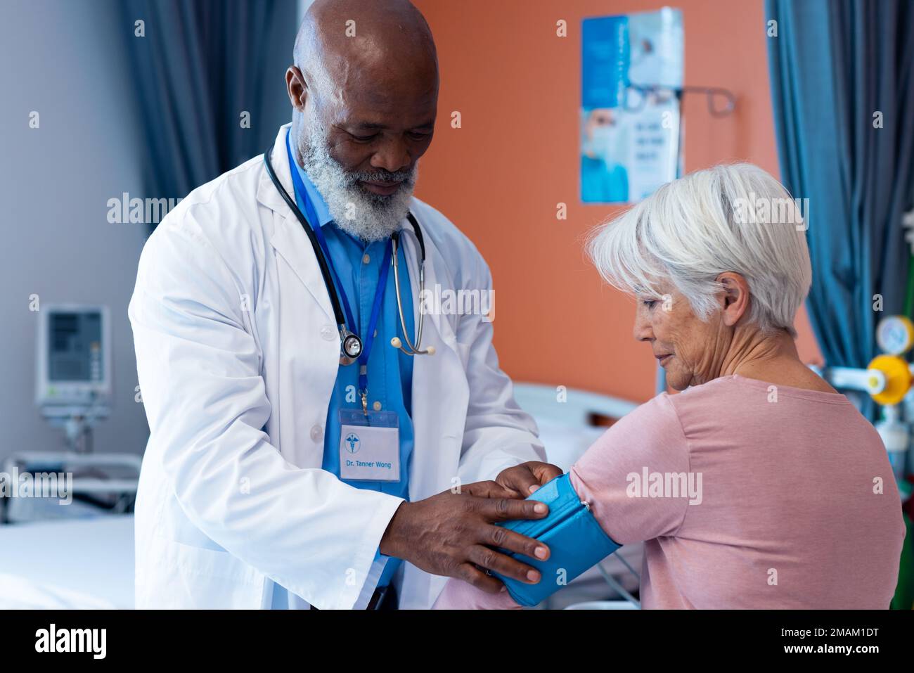 Happy diverse senior male doctor taking blood pressure of senior female ...
