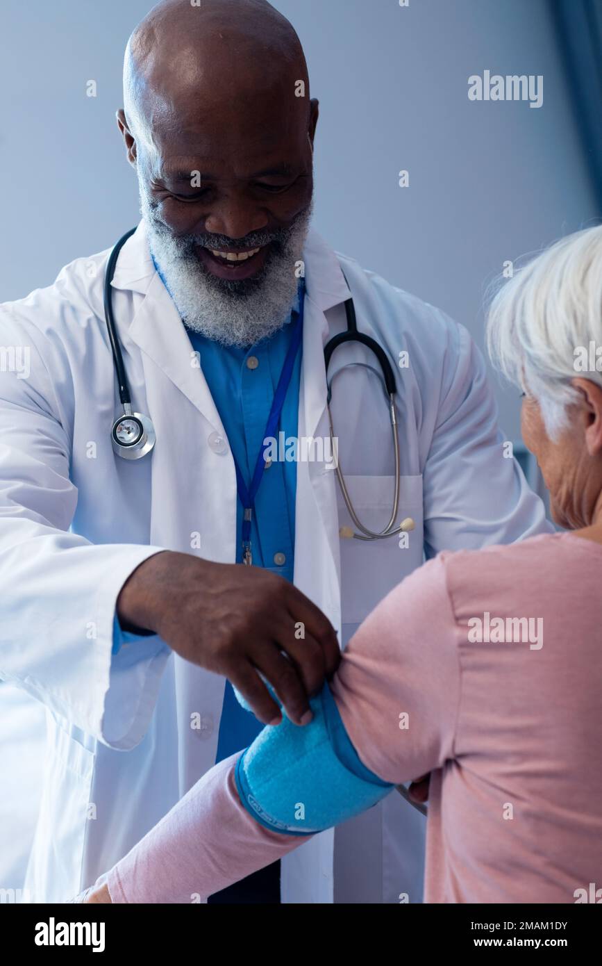 Vertical of happy diverse senior male doctor taking blood pressure of ...
