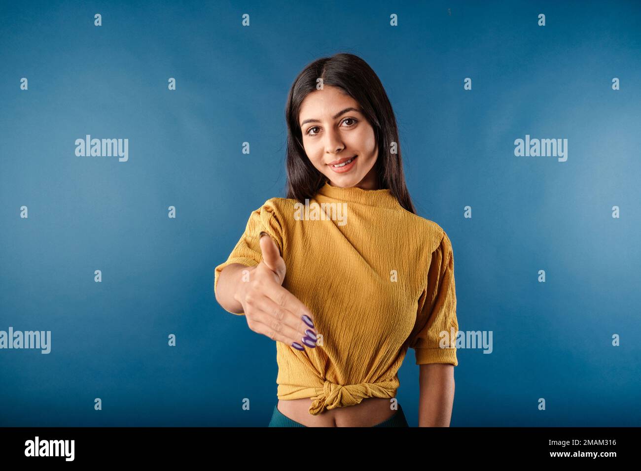 Brown-haired woman wearing mustard yellow t-shirt isolated over blue ...