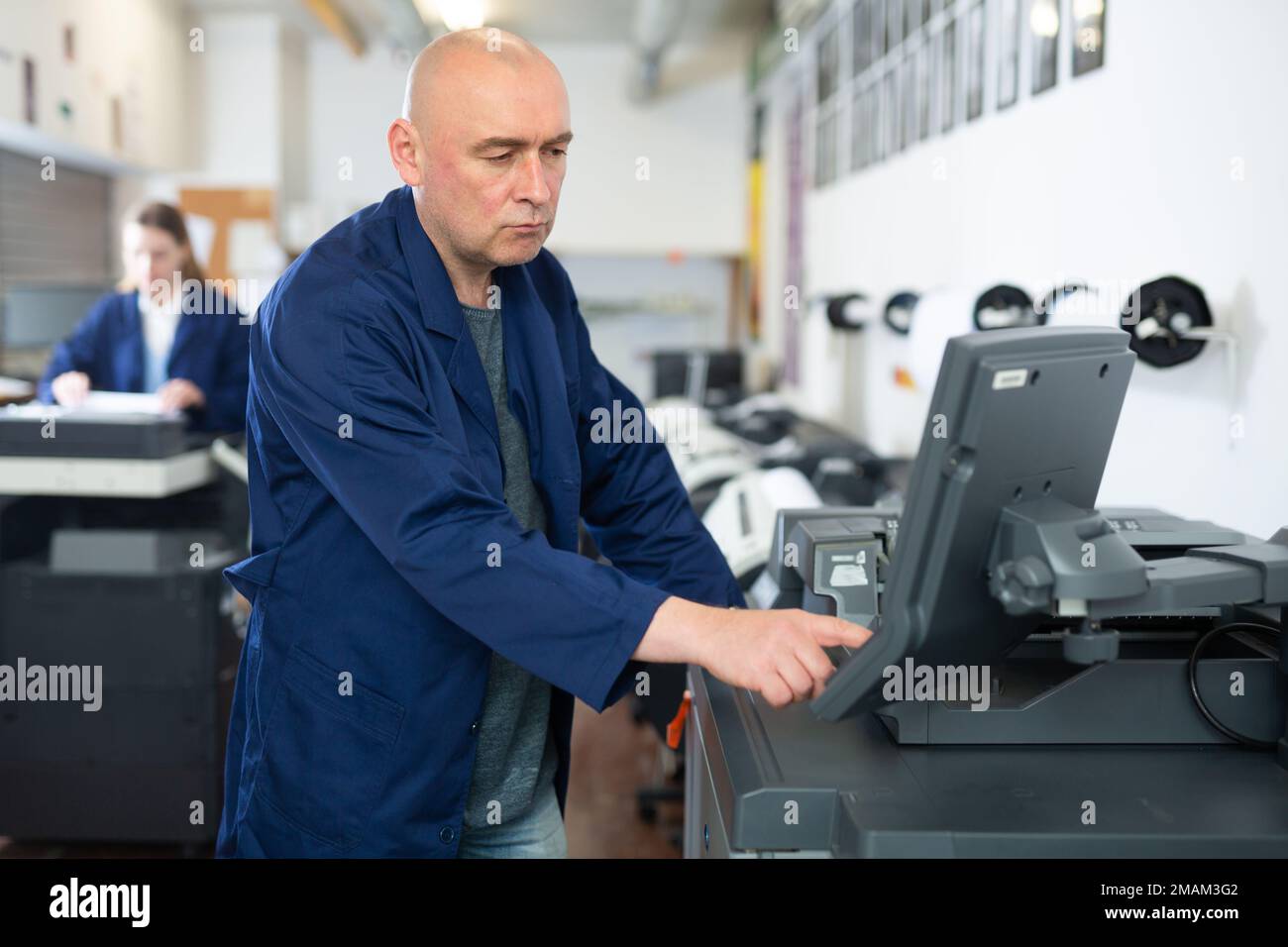 Printing house employee works on printing equipment Stock Photo - Alamy