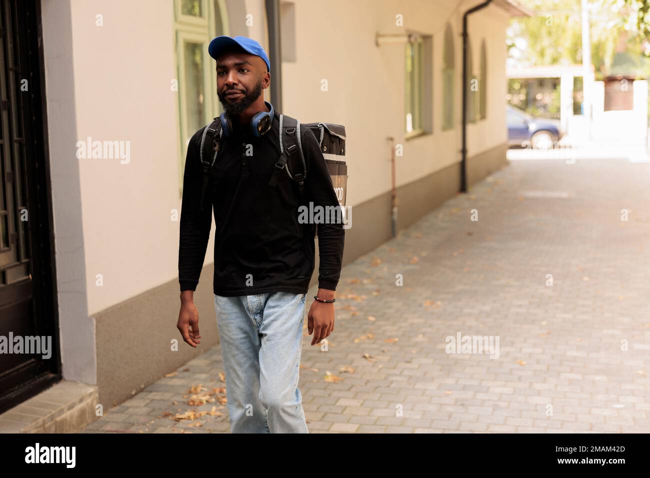 Food delivery by foot, african american courier walking with thermal ...