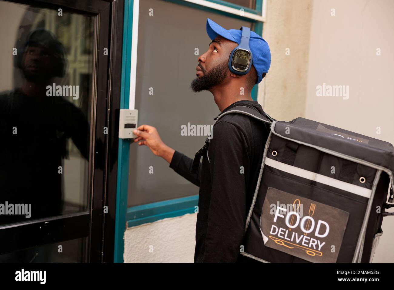 Office meal delivery service courier ringing building doorbell, waiting ...