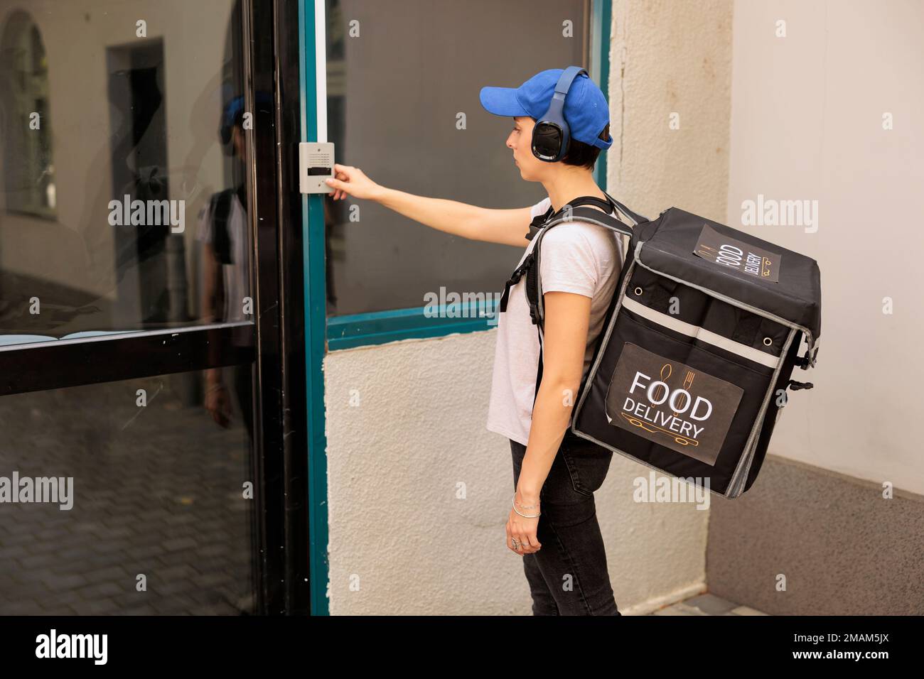 Food delivery service woman courier ringing building doorbell, waiting ...