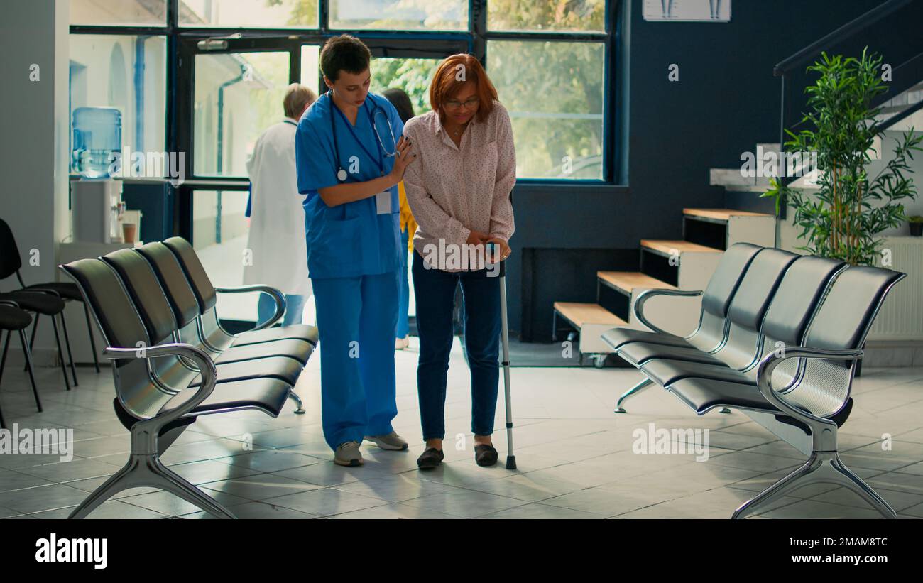Nurse giving support to patient with impairment trying to walk with ...