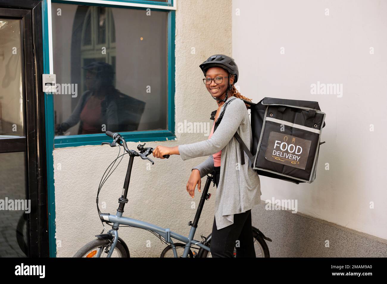 Smiling woman delivering food, courier looking at camera, waiting for ...