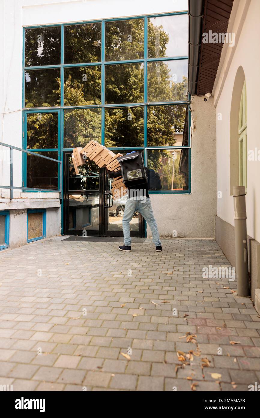 Deliveryman dropping pizza boxes huge pile back view, clumsy courier ...